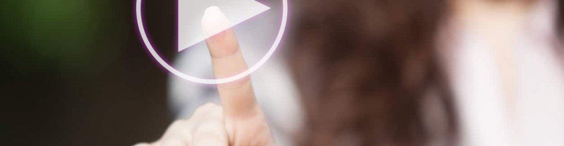 Finger pressing play button on touch screen. | Studer Education